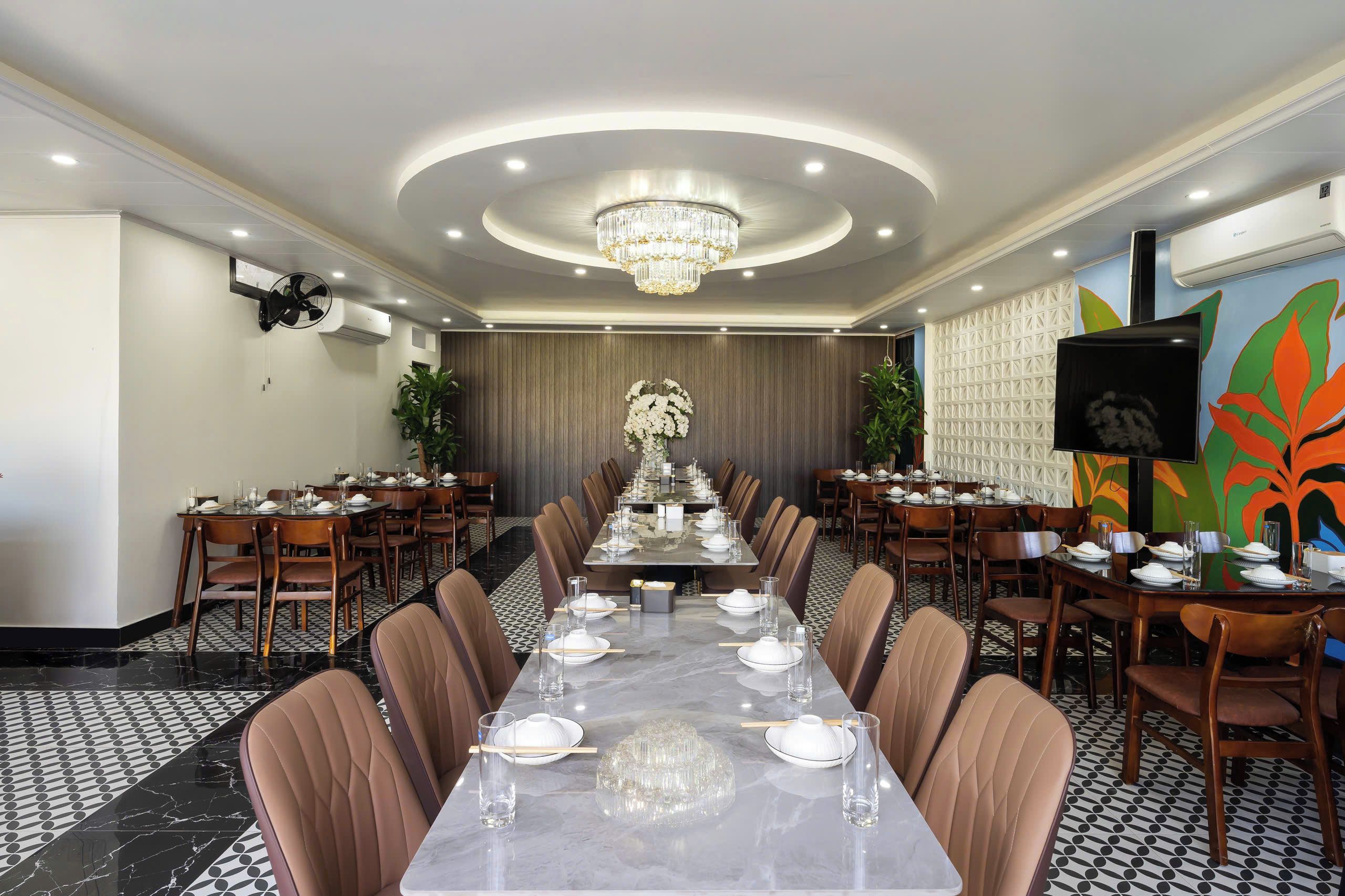 Uma sala de conferência com uma longa mesa posta para uma reunião, cercada por cadeiras, com um candelabro e unidades de ar condicionado nas paredes.
