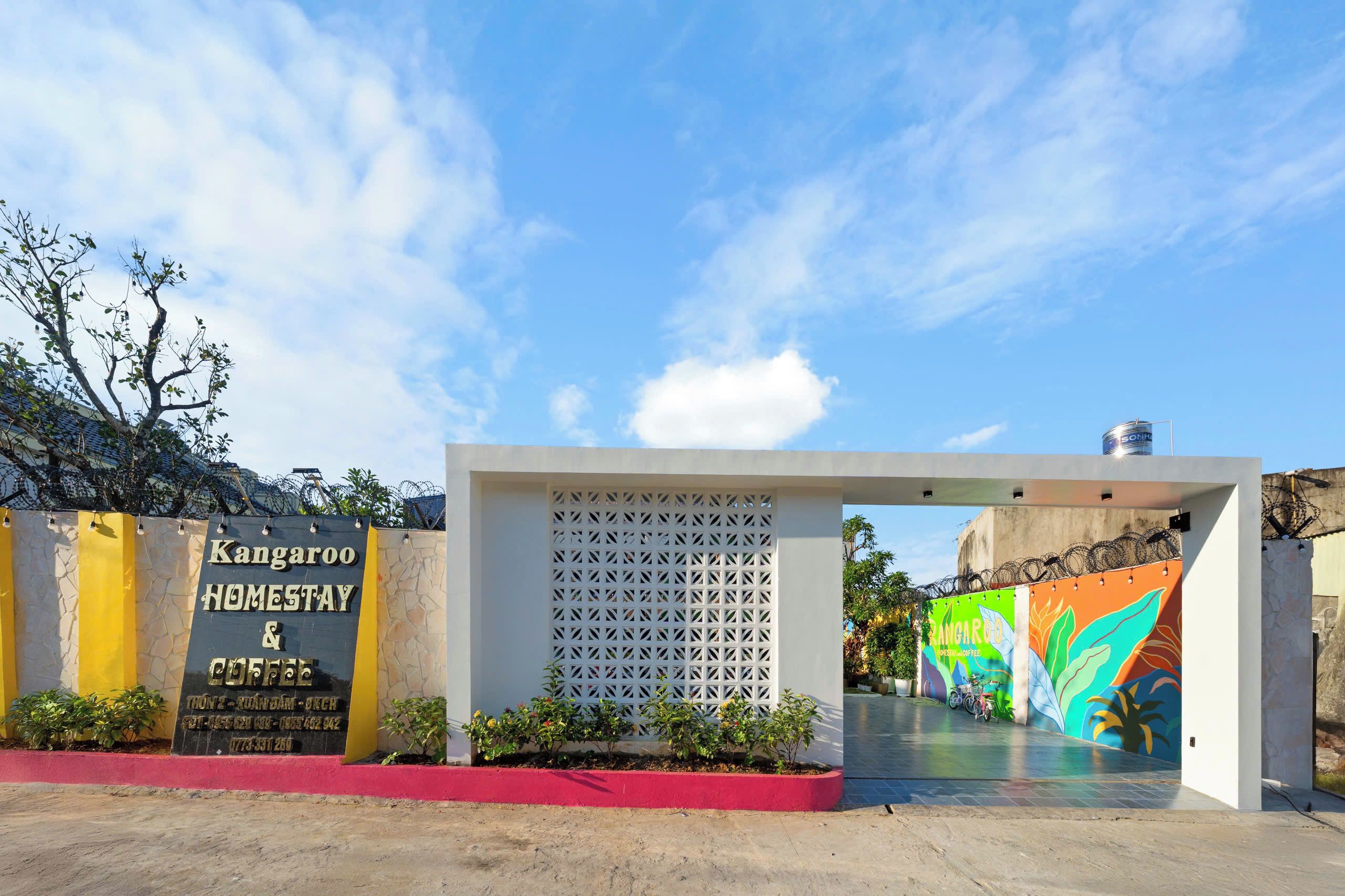 Entrada de um prédio com placa de 'Kangaroo Homestay & Coffee' e um mural colorido na parede.