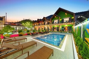 Hotel com piscina, área de estar externa e fachada colorida.