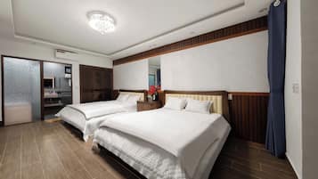 Quarto de hotel com duas camas, piso de madeira, luminária no teto e espelho na parede.