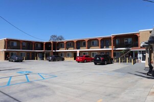 Um motel com vários quartos, estacionamento e alguns carros estacionados.