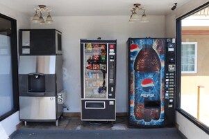 Quarto com dispensador de água, máquina de bebidas e máquina de Pepsi.