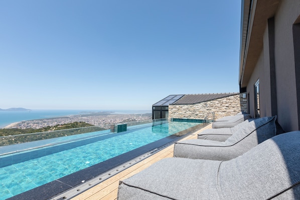Piscina infinita no terraço com vista desobstruída para a cidade e o mar.
