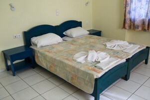 Uma cama de solteiro com colcha, duas mesas de cabeceira e uma tomada na parede.