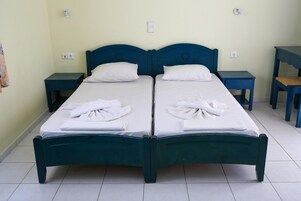 Quarto com duas camas de solteiro, duas mesas de cabeceira, uma cadeira e uma mesa.