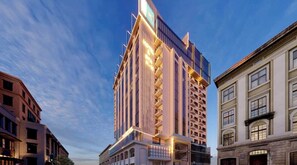 Hotel de vários andares com design moderno, apresentando varandas e uma entrada imponente.