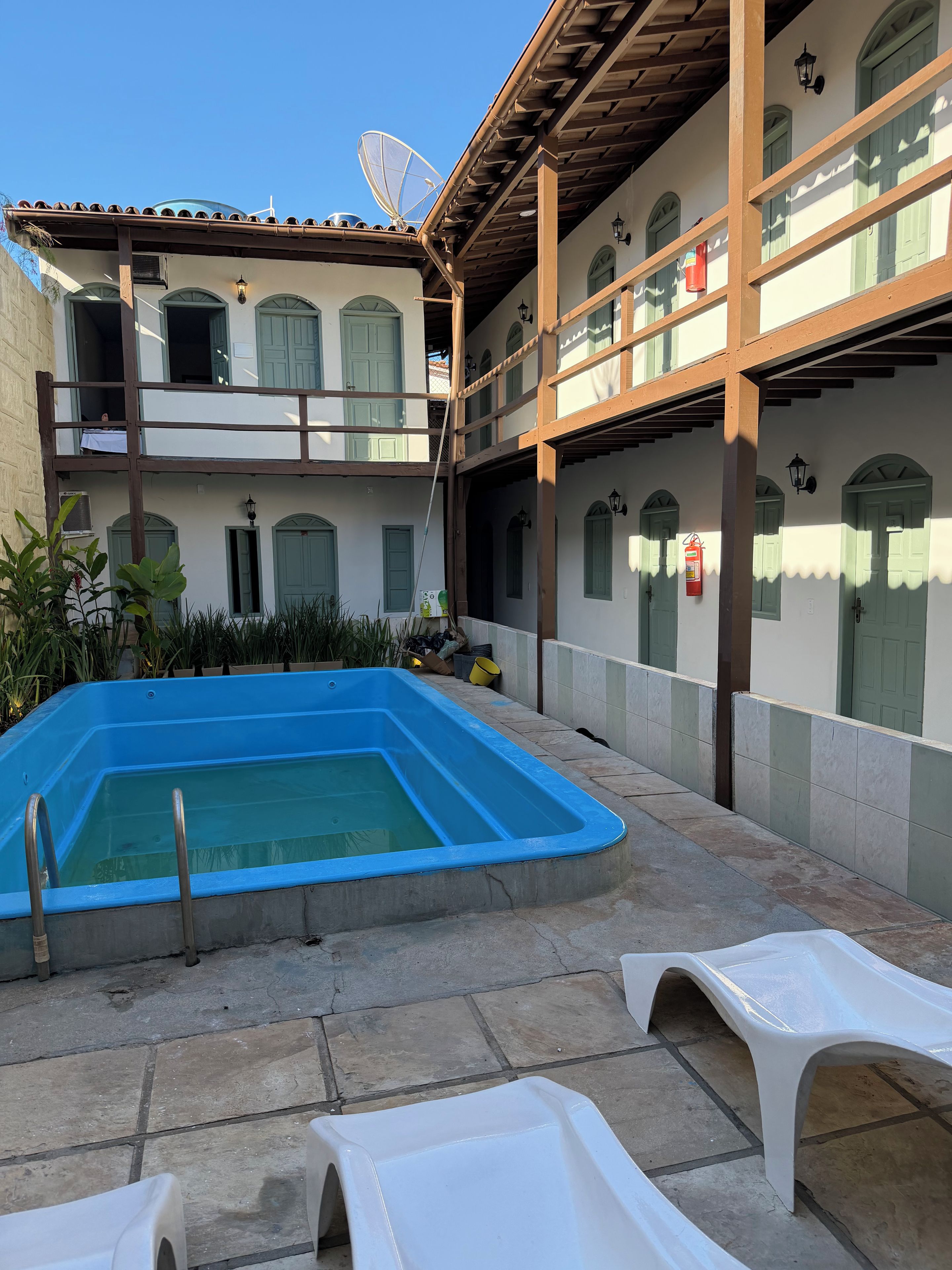 Um pátio com piscina, área de estar ao ar livre e um edifício com várias varandas.