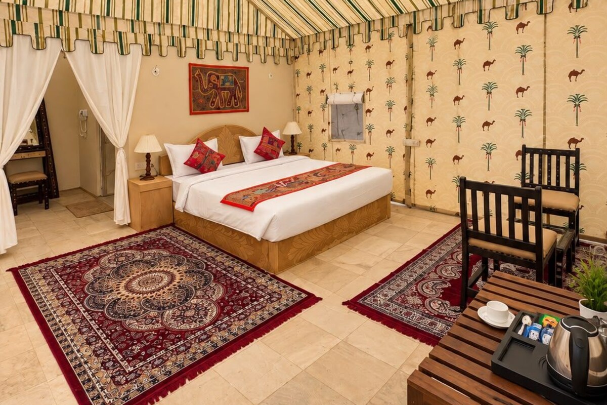 Um quarto coberto por uma tenda, com uma cama, uma mesa e uma cadeira.