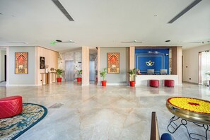 Um hall amplo com balcão de recepção, área de estar e painéis decorativos.