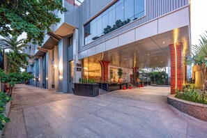 Um edifício moderno com entrada coberta, área de estar ao ar livre e plantas em vasos.
