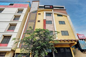 Um edifício de vários andares com uma placa grande de 'OYO Hotel', apresentando um design moderno com uma combinação de fachada de tijolo e revestimento de gesso.