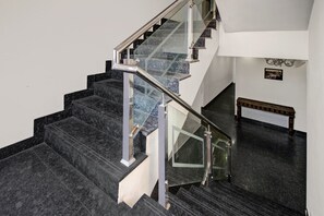 Escadaria com guarda-corpos de vidro e degraus de mármore.