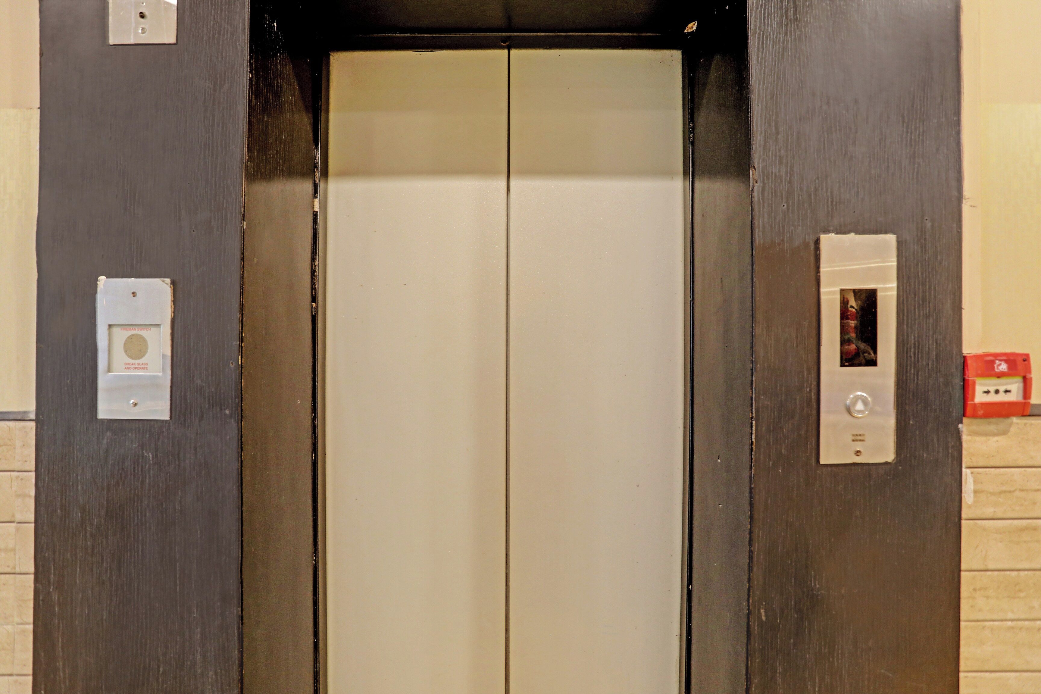 Um elevador com painel de controle à esquerda e botão à direita.