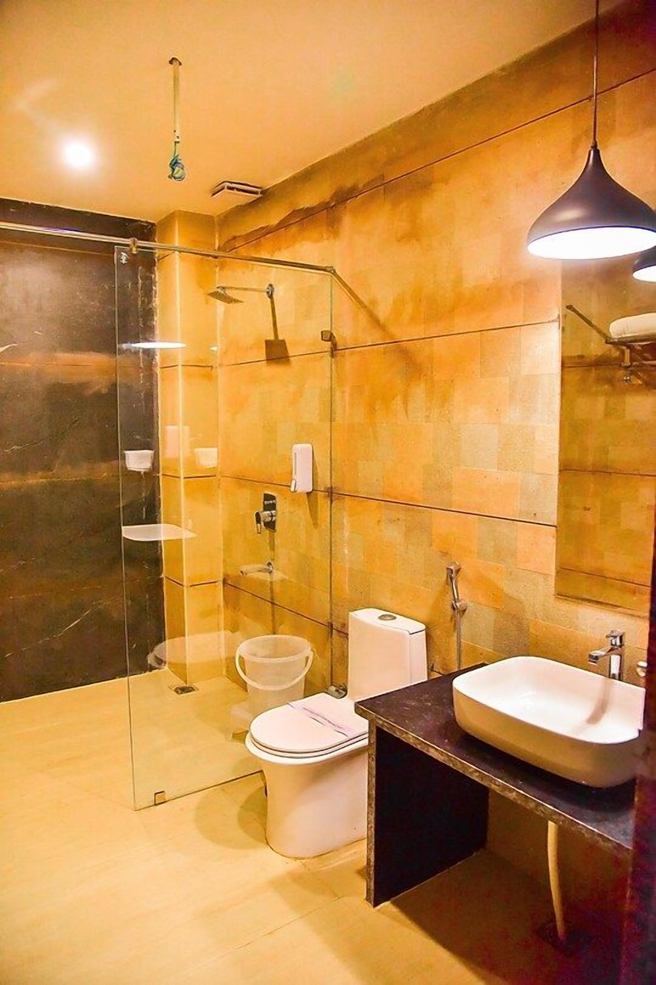 Uma casa de banho moderna com cabine de chuveiro em vidro, sanita, lavatório e espelho.