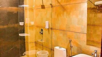 Uma casa de banho moderna com cabine de chuveiro em vidro, sanita, lavatório e espelho.