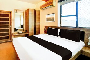 Quarto de hotel com cama, guarda-roupa, espelho, quadro na parede e janela com vista.