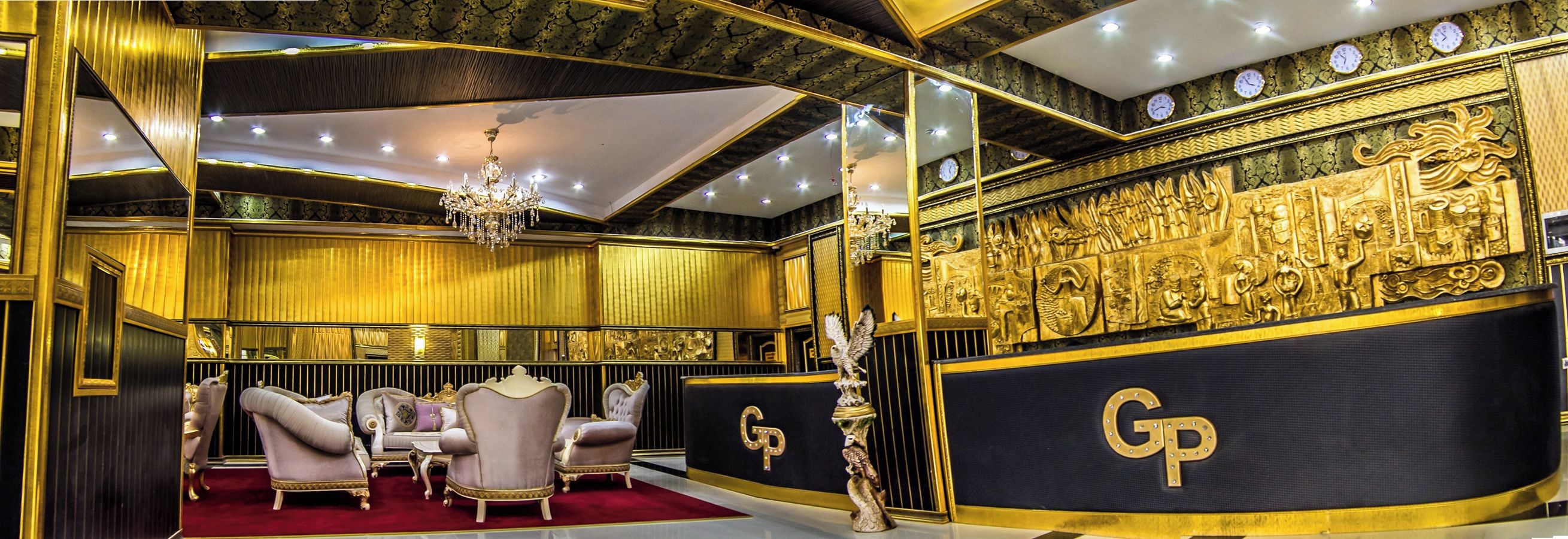 Quarto luxuoso com carpete vermelho, detalhes dourados e um candelabro.