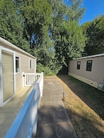 Casa móvel com varanda coberta e área de deck cercada.