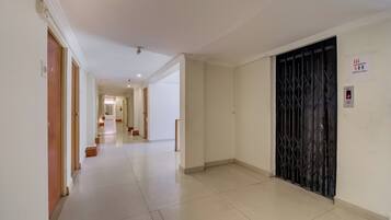 Corredor de hotel com um portão de metal preto, placa de ocupação máxima e um visor digital exibindo o número 2.