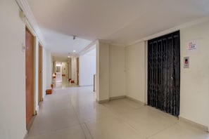 Corredor de hotel com um portão de metal preto, placa de ocupação máxima e um visor digital exibindo o número 2.