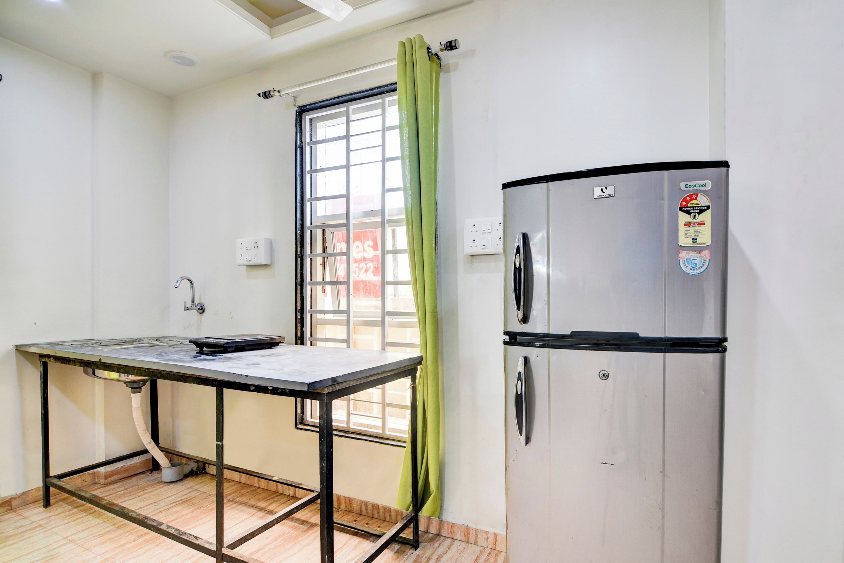 Uma pequena cozinha compacta com geladeira de aço inoxidável, pia e mesa.