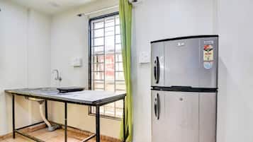 Uma pequena cozinha compacta com geladeira de aço inoxidável, pia e mesa.