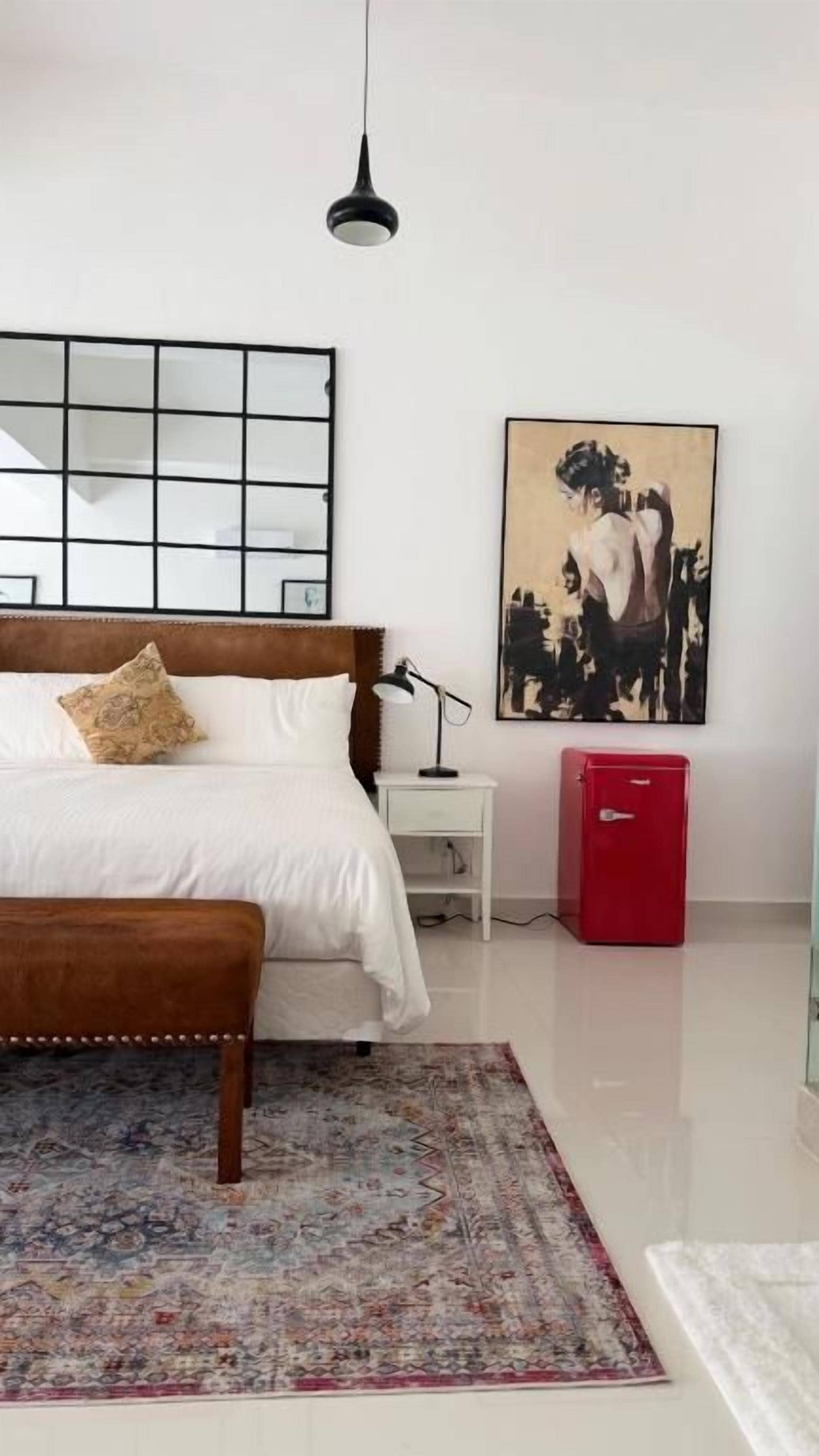 Quarto com cama, mesa de cabeceira, luminária e um armário vermelho.