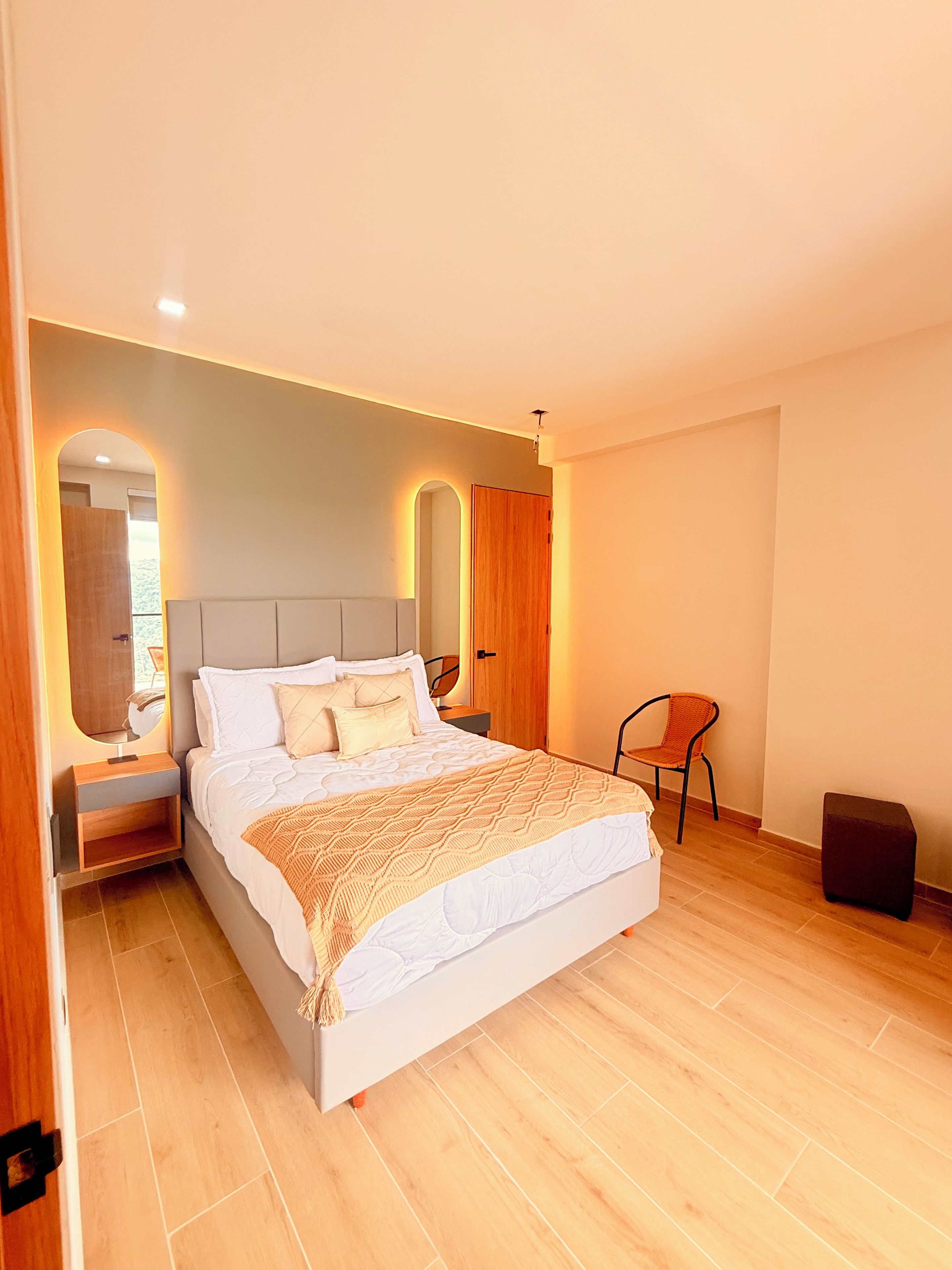 Quarto moderno com uma cama grande, mesa de cabeceira, uma cadeira e um guarda-roupa.
