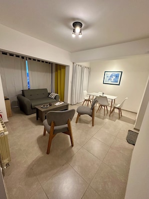 Uma sala de estar moderna com sofá, mesa de centro e área de jantar com cadeiras.