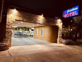 Um motel com fachada de pedra, letreiro de neon e estacionamento.