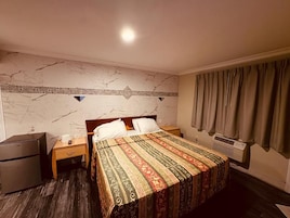 Quarto de hotel com cama, mesa de cabeceira, aquecedor e guarda-roupa.