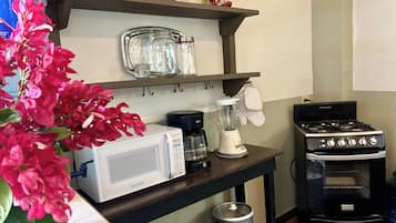 Uma cozinha equipada com micro-ondas, cafeteira, chaleira e fogão.
