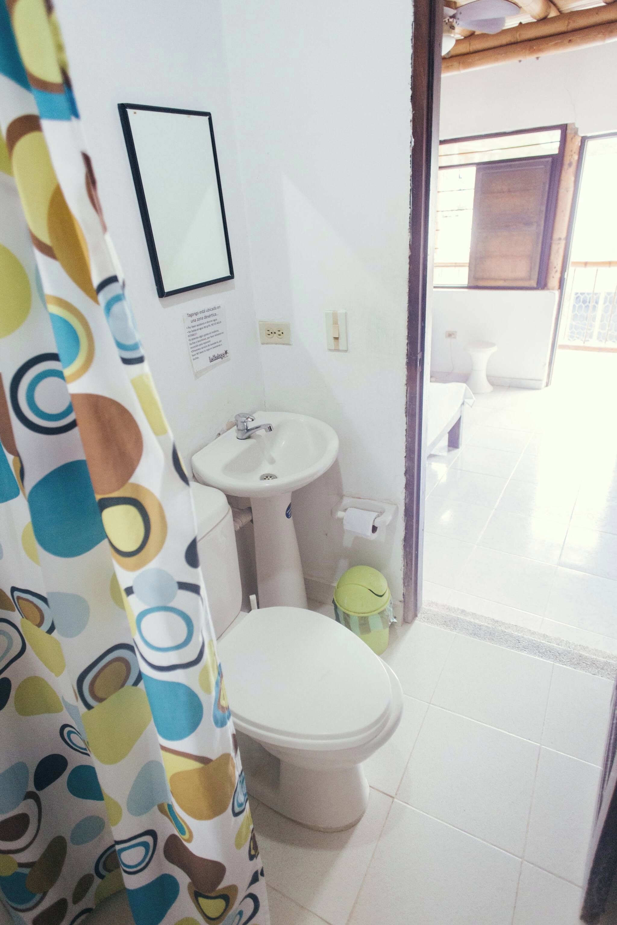 Casa de banho com sanita, lavatório e um contentor de lixo.