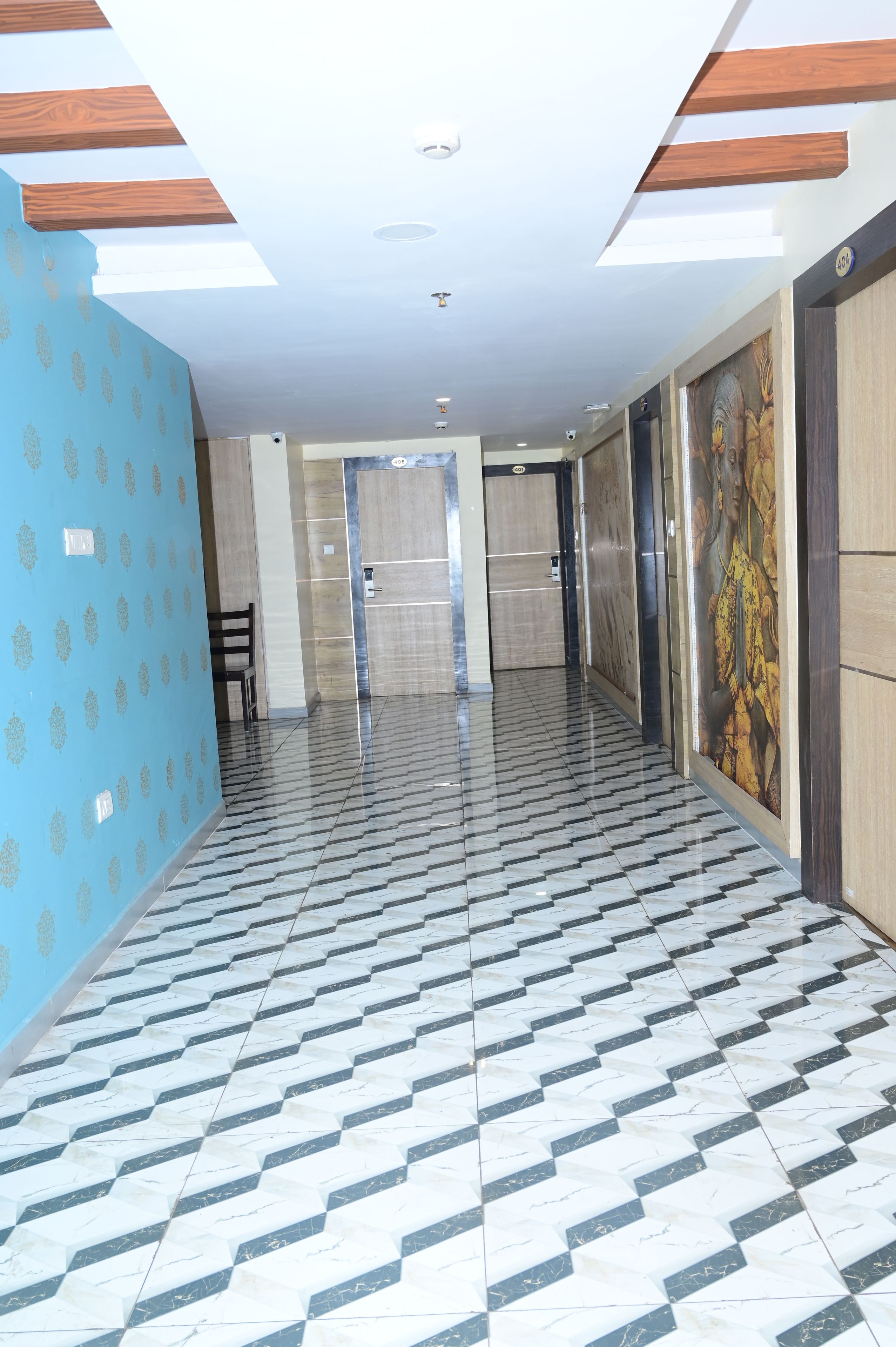 Um corredor com piso estampado, parede azul com padrão floral e uma porta numerada.