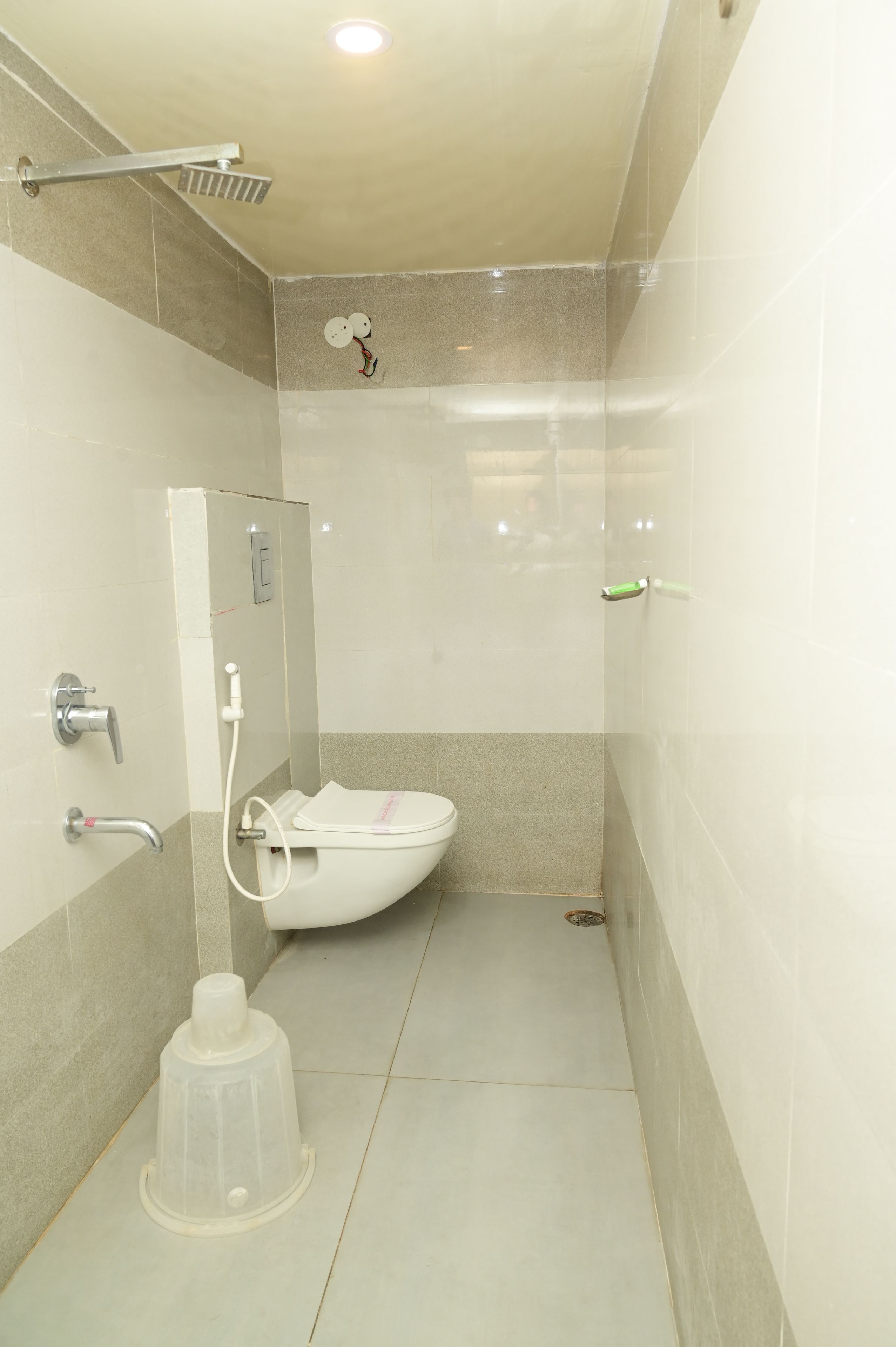 Um banheiro pequeno com azulejos, vaso sanitário, chuveiro e secador de mãos.