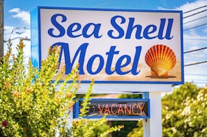 Placa de motel com o nome 'Sea Shell Motel' e um desenho de concha.