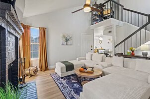 Uma sala de estar ampla com escada moderna, lareira e vista para o exterior.