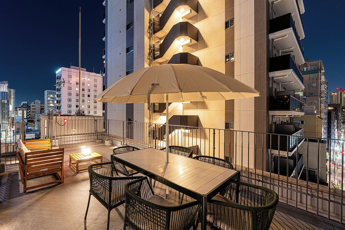 Terraço no telhado com mesa, cadeiras, um banco e um guarda-sol.