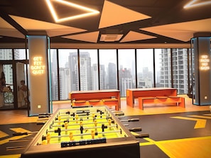 Quarto com mesa de futebol de mesa, bancos e arte inspiradora na parede.