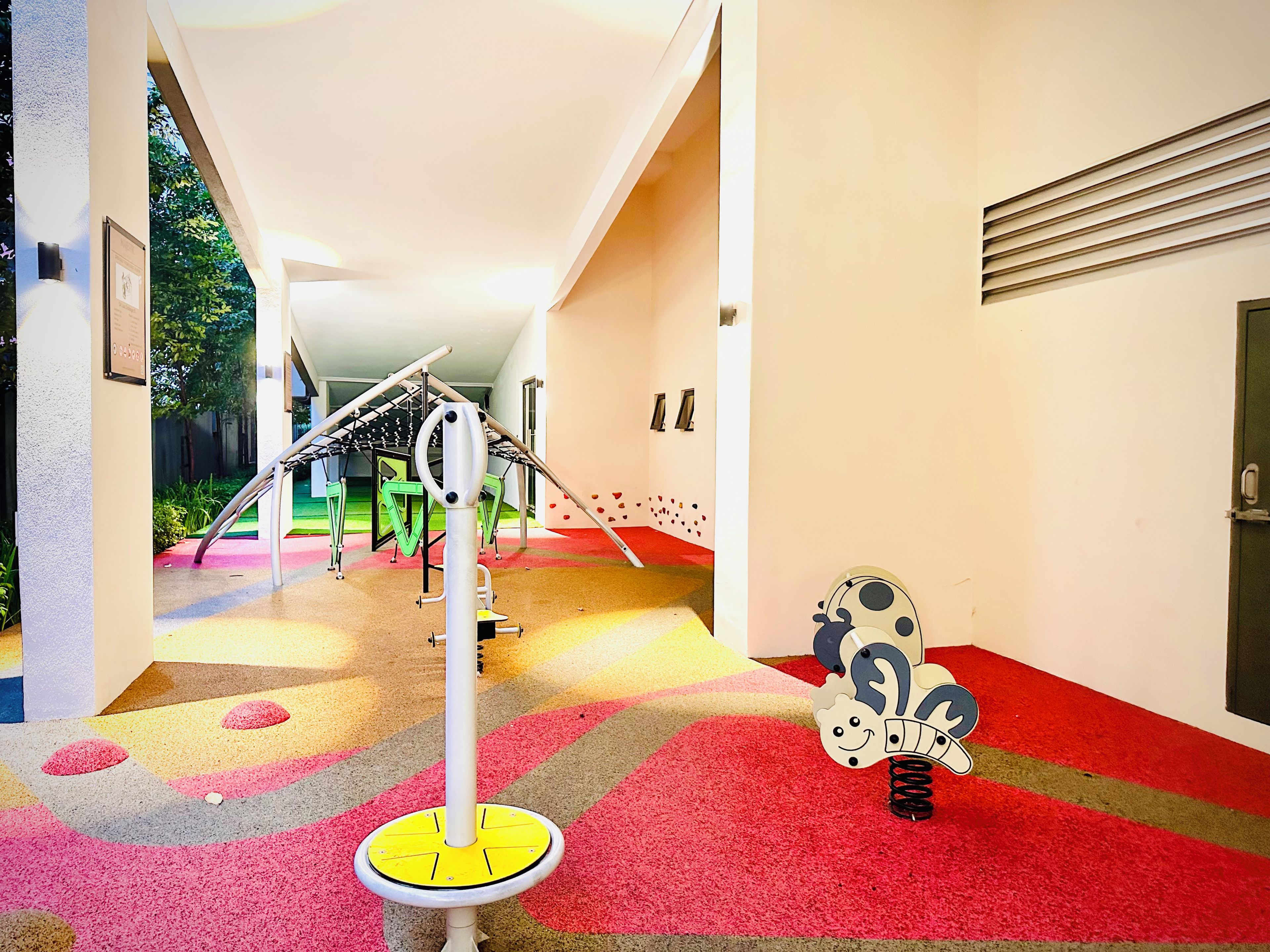 Espaço infantil com estrutura de escalada e piso acolchoado.