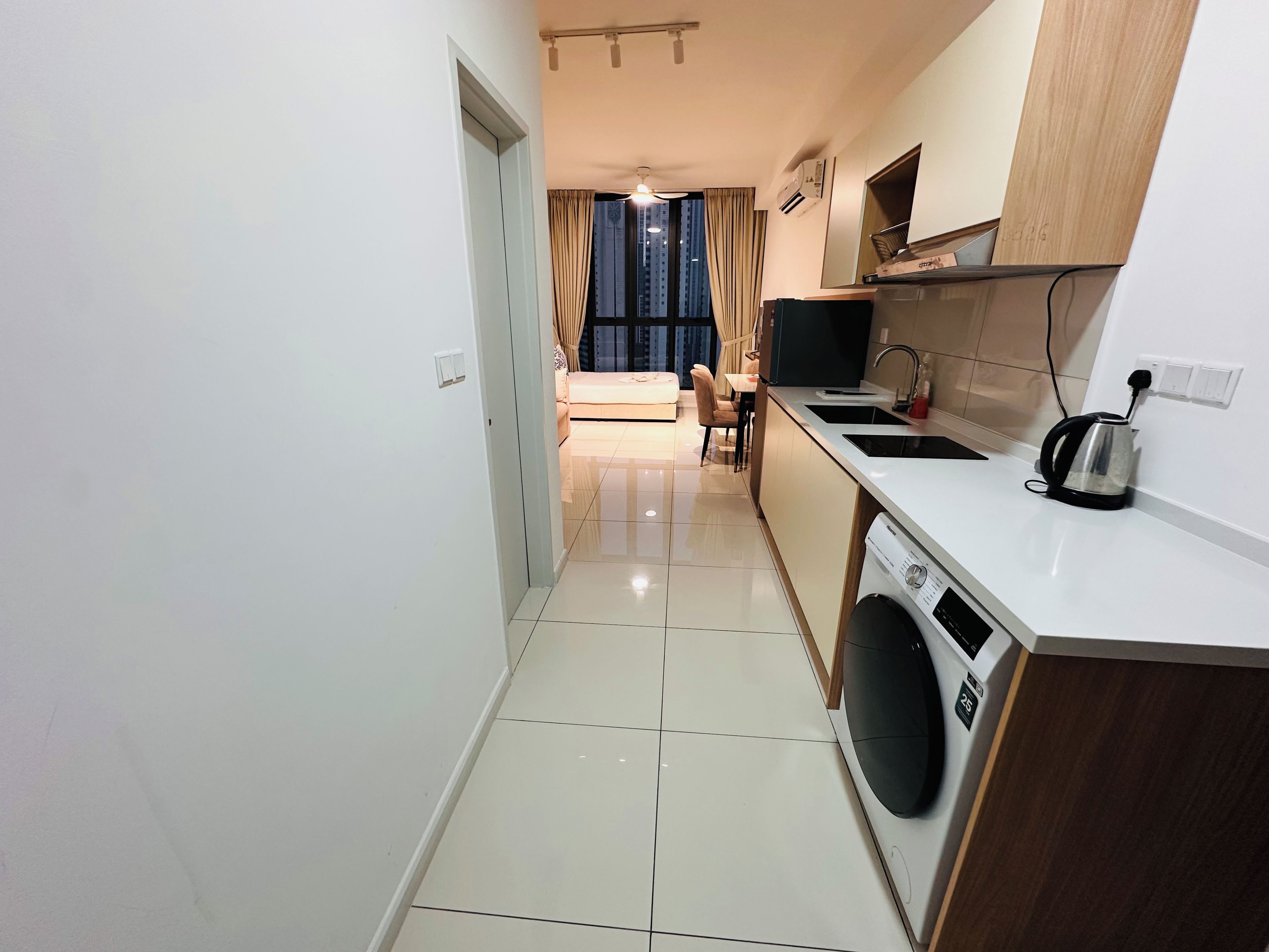 Cozinha moderna com máquina de lavar, chaleira e área de refeições com mesa e cadeiras.