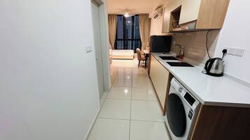 Cozinha moderna com máquina de lavar, chaleira e área de refeições com mesa e cadeiras.