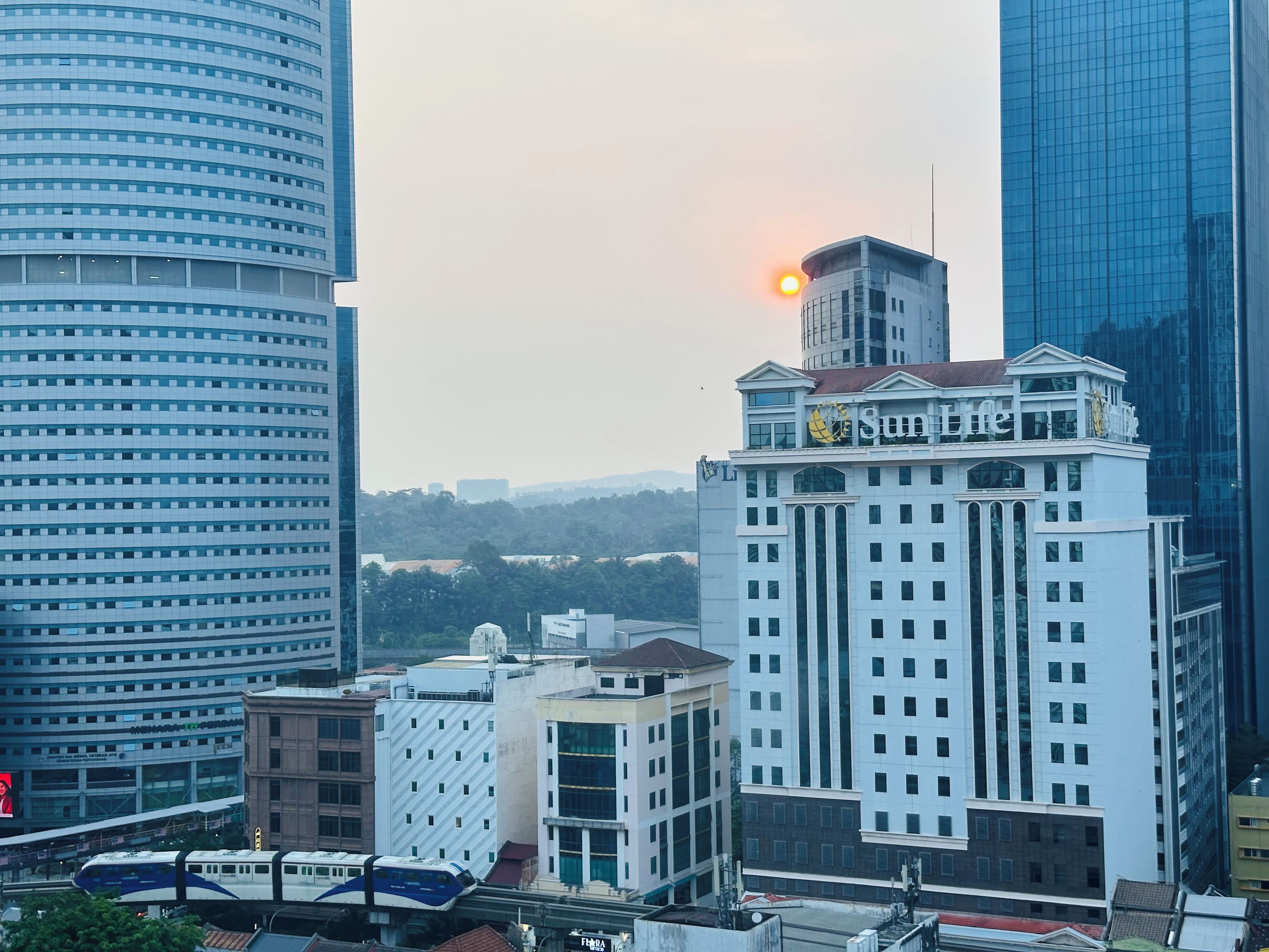 Um edifício moderno com uma placa grande da 'Sun Life', rodeado por outros edifícios altos.