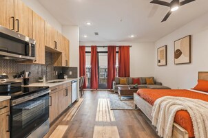 Um apartamento moderno com cozinha compacta, sofá, cama e área de jantar.