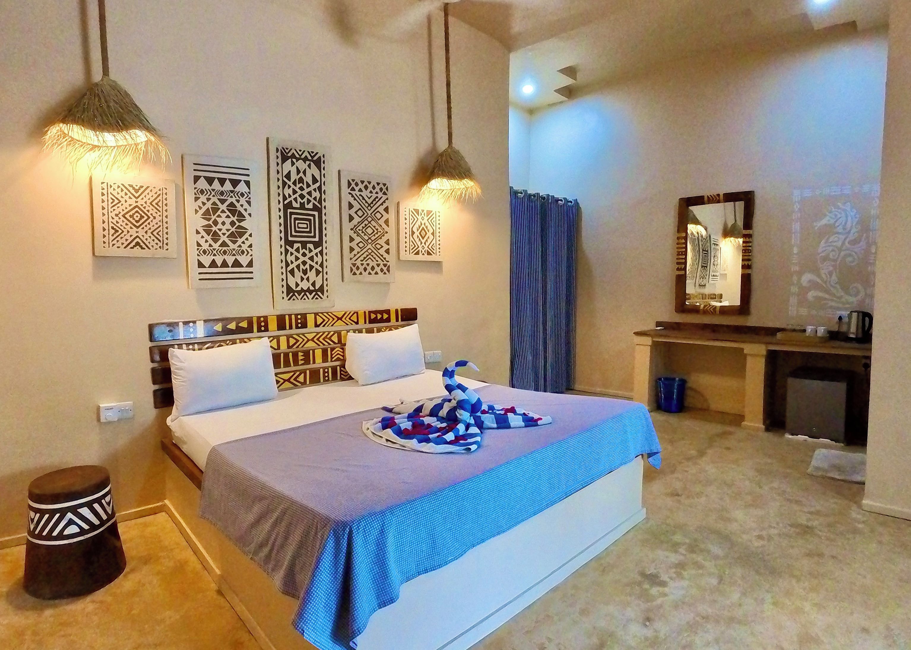 Quarto de hotel com cama, mesa de cabeceira, espelho e obras de arte nas paredes.