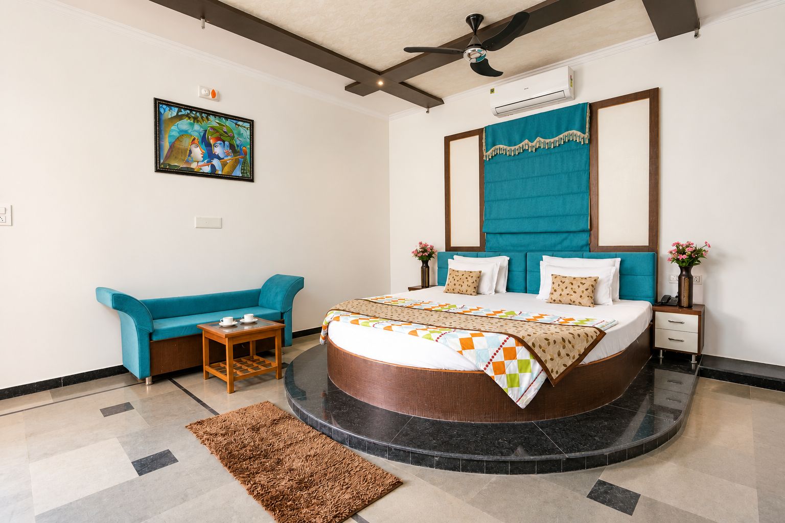 Quarto de hotel com cama, sofá, mesa pequena e pintura na parede.