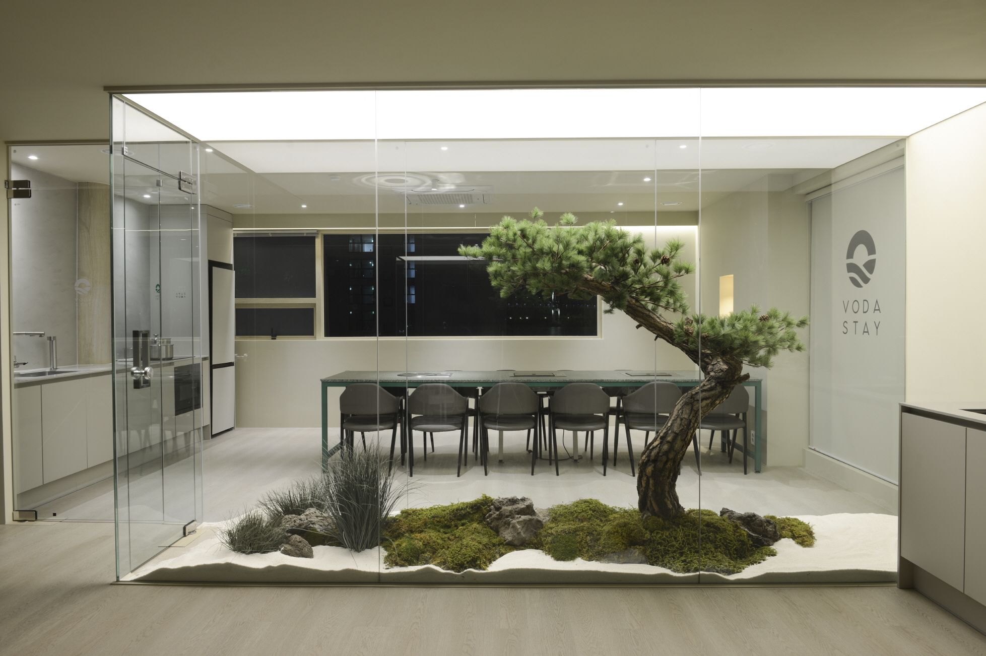 Uma sala de reunião moderna com divisória de vidro, mesa de madeira e cadeiras.