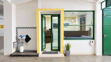 Uma área de recepção com entrada por porta de vidro, balcão de recepção e planta em vaso.