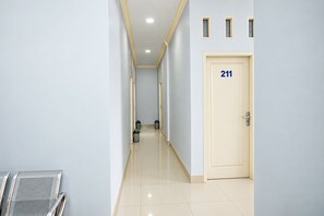 Corredor com uma porta identificada como '211' e lixeiras ao longo da parede.