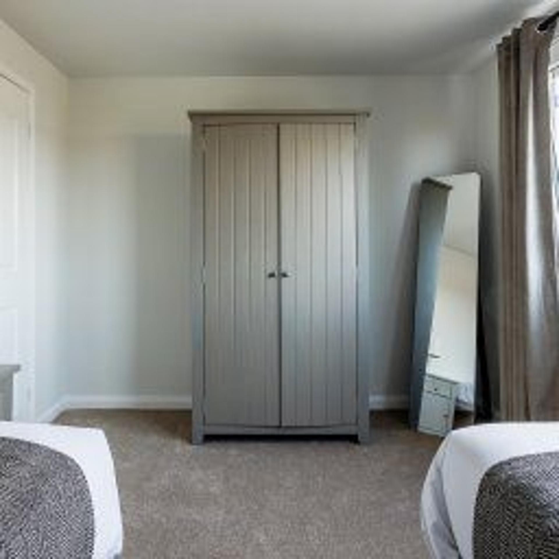 Quarto com guarda-roupa, cama e espelho.